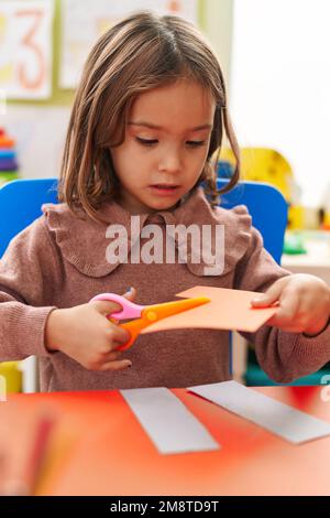 Adorable hispanic girl student sitting on table drawing on paper at ...
