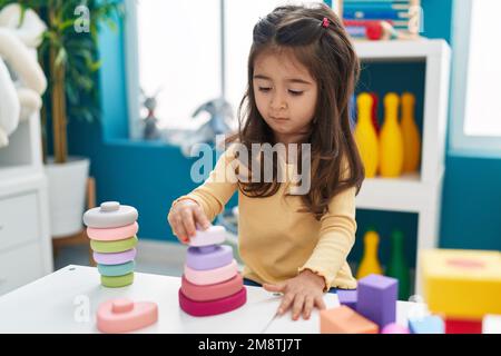 Adorable hispanic girl playing with construction blocks sitting on ...