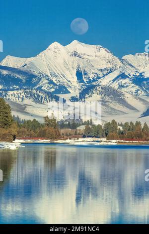 full moon rising over the flathead river and mission mountains in ...