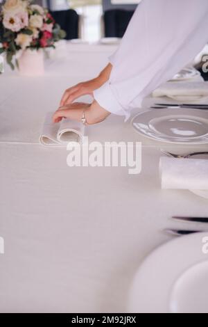 The waiter puts a white napkin on the plate. Beautiful table setting ...