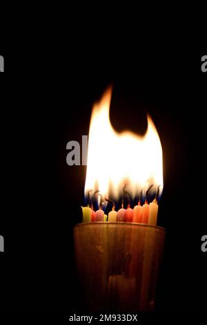 Burning multicolour small thin candle around dark place Stock Photo - Alamy