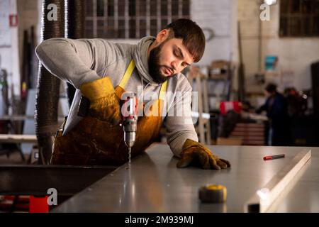 Man engineer drilling metal sheet in workshop Stock Photo - Alamy