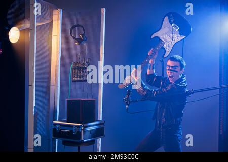 Crazy funky rocker throwing guitar in studio, wearing leather jacket ...