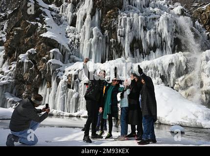 BARAMULLA, INDIA - JANUARY 16: Tourists enjoy near a frozen waterfall ...
