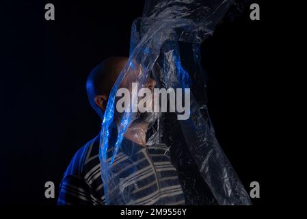 A bald man suffocating with a transparent plastic bag flying over his ...