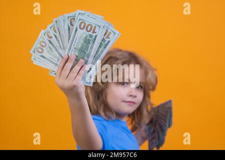 Kid with lots of money dollar banknotes isolated over yellow studio ...