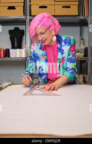 Dressmaker with pink hair and colorfull clothes drawing new layout ...