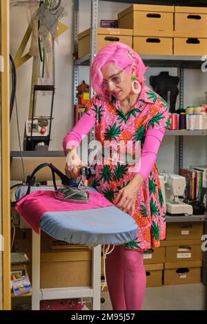 Dressmaker with pink hair and colorfull clothes drawing sewing patterns ...