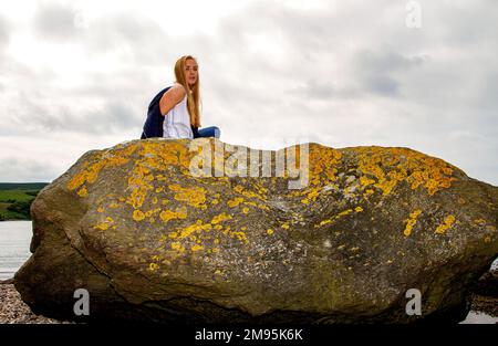 Rhianna Martin, a beautiful blonde woman, sits on rocks while having ...