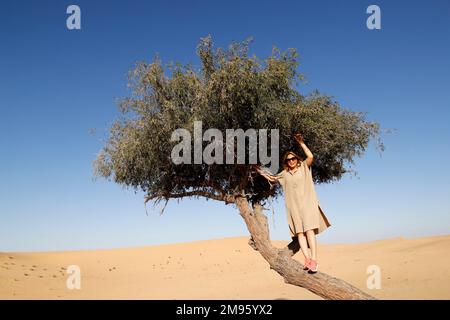 Woman with an acacia tree in Abu Dhabi desert. United Arab Emirates ...