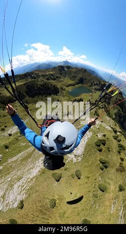 A vertical top view of a skydiver paragliding on a scenic landscape ...