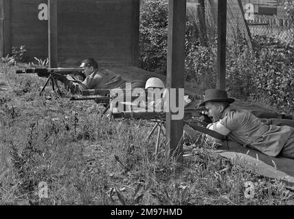 Three men at a shooting range, with rifles, and telescopes on tripods ...
