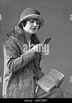 A fashionable young woman checking her makeup in a hand mirror Stock ...