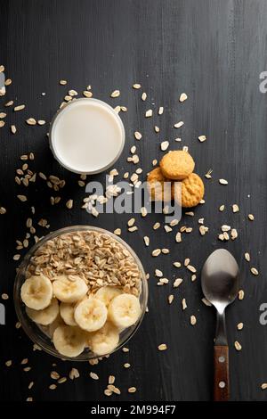 vertical image of a bowl with oatmeal and banana accompanied by a glass ...