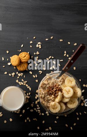 vertical image of a bowl with oatmeal and banana accompanied by a glass ...
