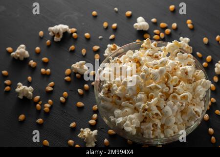 top view of a bowl of freshly popped popcorn on a black table, and copy ...