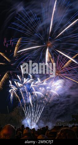 A spectacular vertical view of a crowd watching beautiful fireworks ...