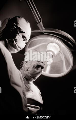 Low angle portrait of two surgeons wearing masks looking down under ...