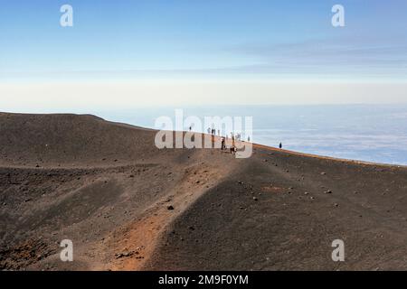 People walking along a ridge ascending to Mount Etna, Europe’s highest ...