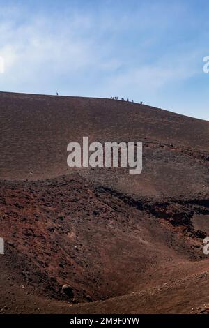 People walking along a ridge ascending to Mount Etna, Europe’s highest ...
