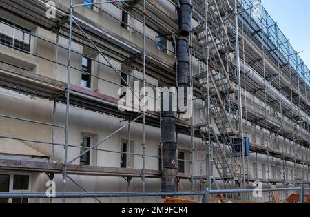 workers on a building with scaffolding and container Stock Photo - Alamy