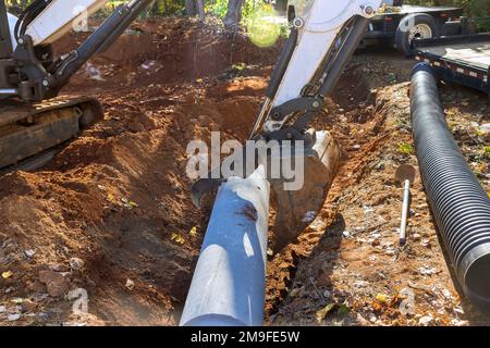 Worker Working With Tractor Lift To Install Sewage Pipes In Ground Is