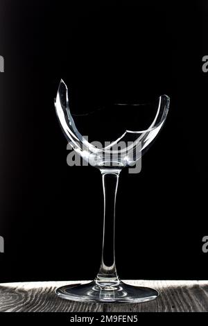 Broken glass goblet. Stands on black boards. Shot on a black background ...