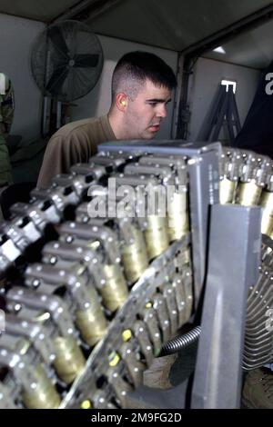 A U.S. Air Force Airman loads empty magazines into ammunition cans ...