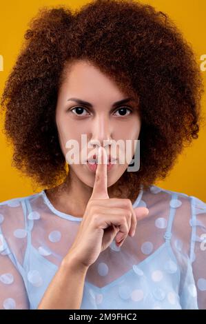 Pretty young woman showing a hush sign Stock Photo - Alamy