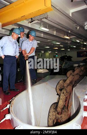 US Navy SEAMAN Kevin Rohrer washes down the anchor chain as it is ...