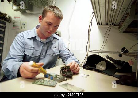 US Navy Electronics Technician Third Class performs maintenance on the ...