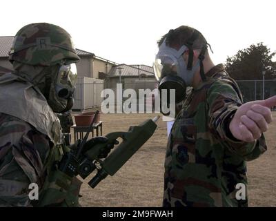 An airman wearing an MCU-2P gas mask aims his M-16 rifle as he lies ...