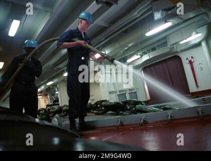 US Navy Seaman washes down an anchor chain from the foc'sle aboard the ...