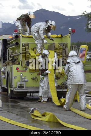 Firefighters in protective gear are responding to a building fire, with ...