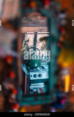 A vertical shot of the reflection of a kettle on a stove in the mirror ...
