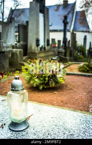 Candle lantern at grave in cemetery. Grief and paying respect for dead person. Tombstones and a ...