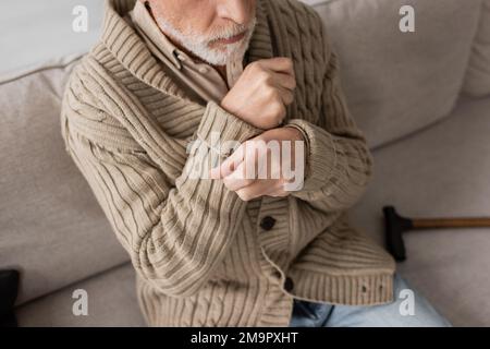 senior man in knitted cardigan holding pills container in trembling ...