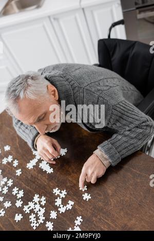 man with disability and parkinson syndrome sitting near jigsaw puzzle ...