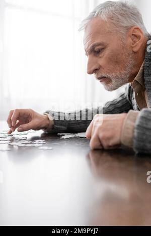 side view of aged man with alzheimer disease looking away near window ...