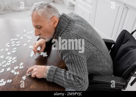 man with disability and parkinson syndrome sitting near jigsaw puzzle ...