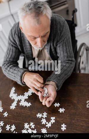 man with disability and parkinson syndrome sitting near jigsaw puzzle ...