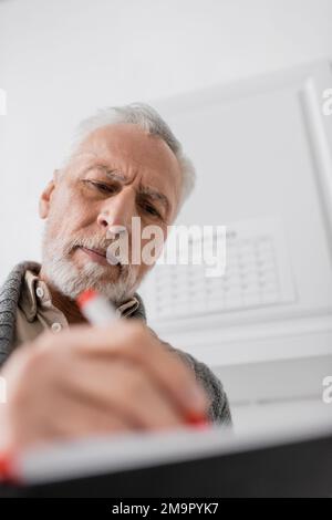senior man with alzheimer syndrome writing on sticky note near blank ...