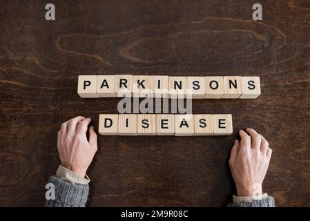 top view of cropped man with parkinsonism and trembling hands near grey ...