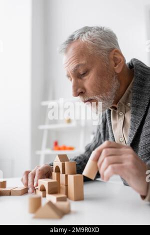 senior man with alzheimer syndrome playing buildings blocks game at ...