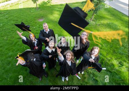 Classmates in graduation gowns throw their caps. View from above Stock ...