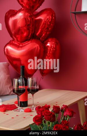 Envelopes with bottle of wine, gift and glasses on pink background ...