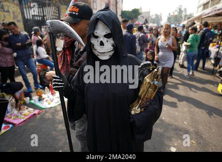 A devotee holds an ornately decorated statue of the "Santa Muerte," or ...