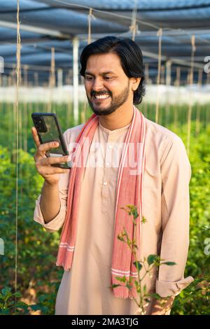 vertical shot of farmer busy using mobile phone at agricultural farm ...