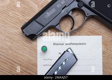 A closeup shot of a small black Rohm brand pistol and a german license ...