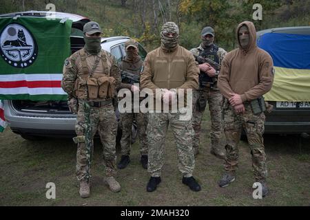Volunteer soldiers pose with a flag of Chechen Republic of Ichkeria ...